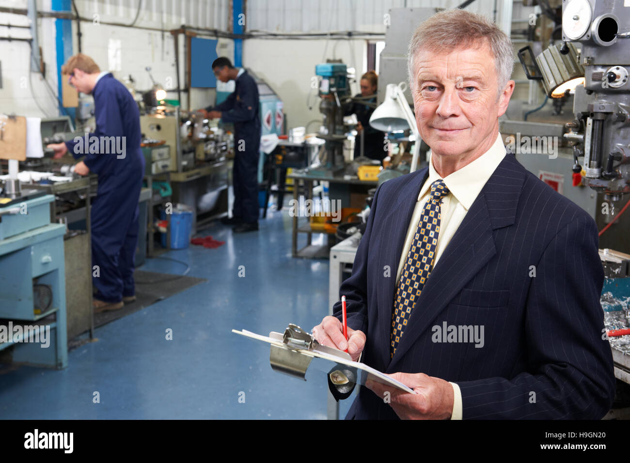 Owner Of Engineering Factory With Staff In Background Stock Photo - Alamy