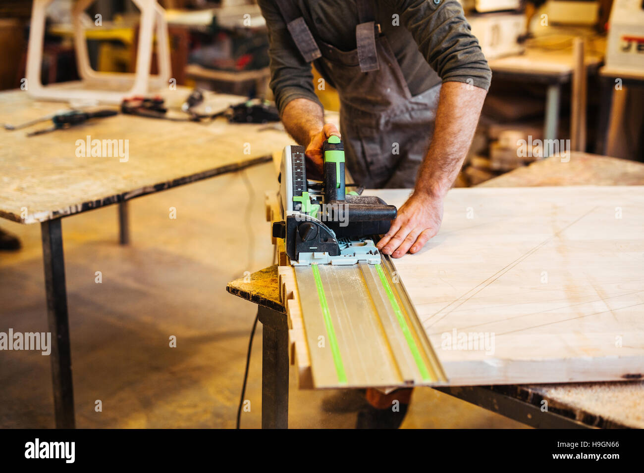 Owner of workshop sawing wooden board on workbench Stock Photo - Alamy
