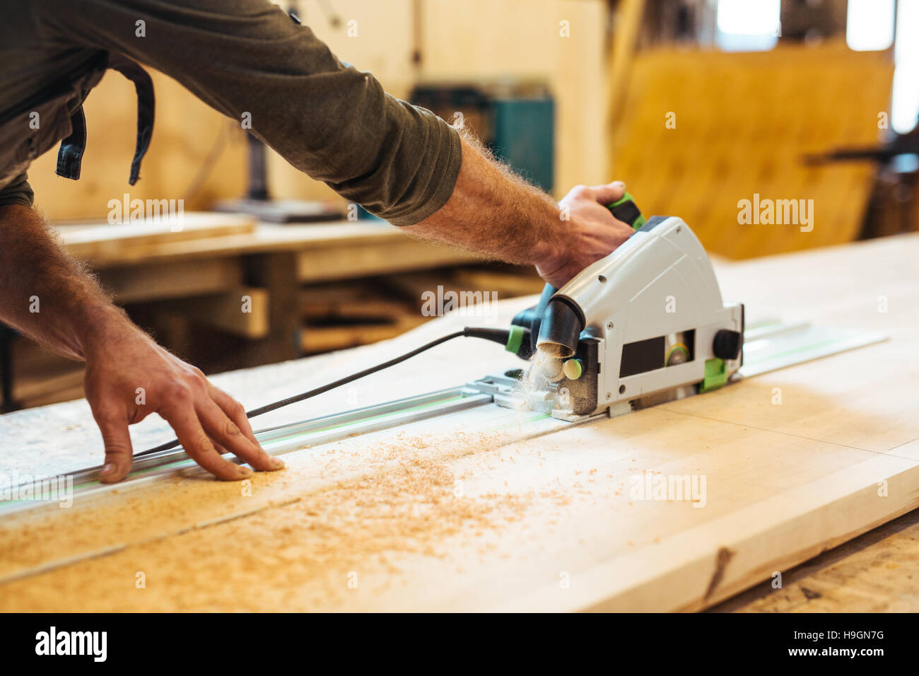 Man sawing wooden board in his workshop Stock Photo - Alamy