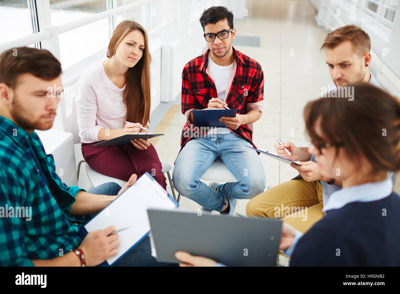 Students looking at something on paper being shown by their teacher ...
