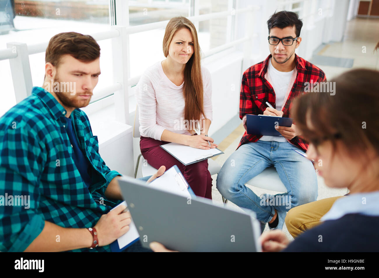 Puzzled students looking at picture on paper and thinking of their ...