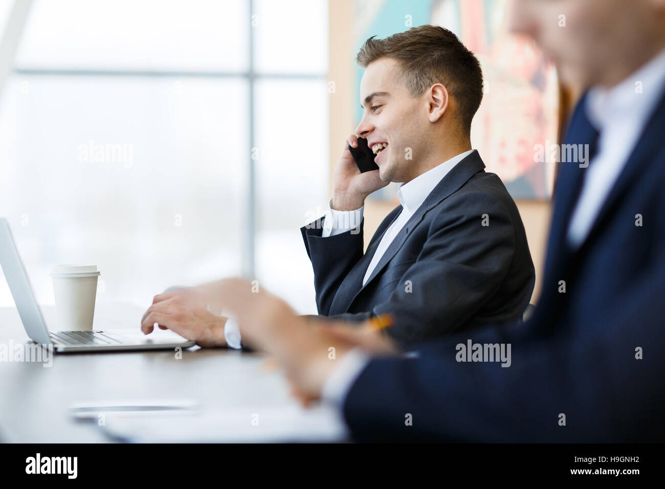 Young trader speaking on the phone and browsing in laptop Stock Photo ...