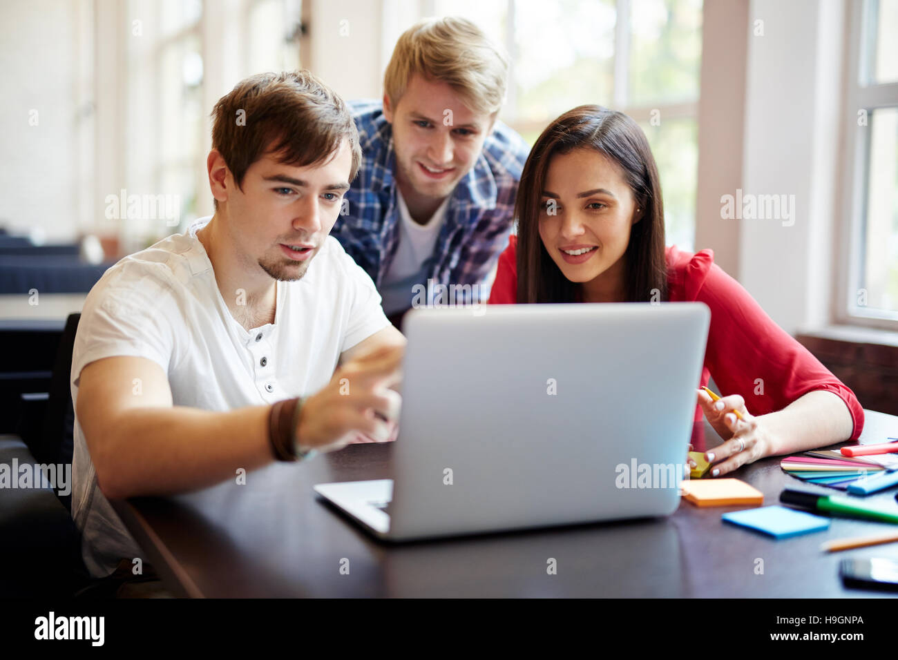 Two guys and girl browsing in the internet Stock Photo - Alamy