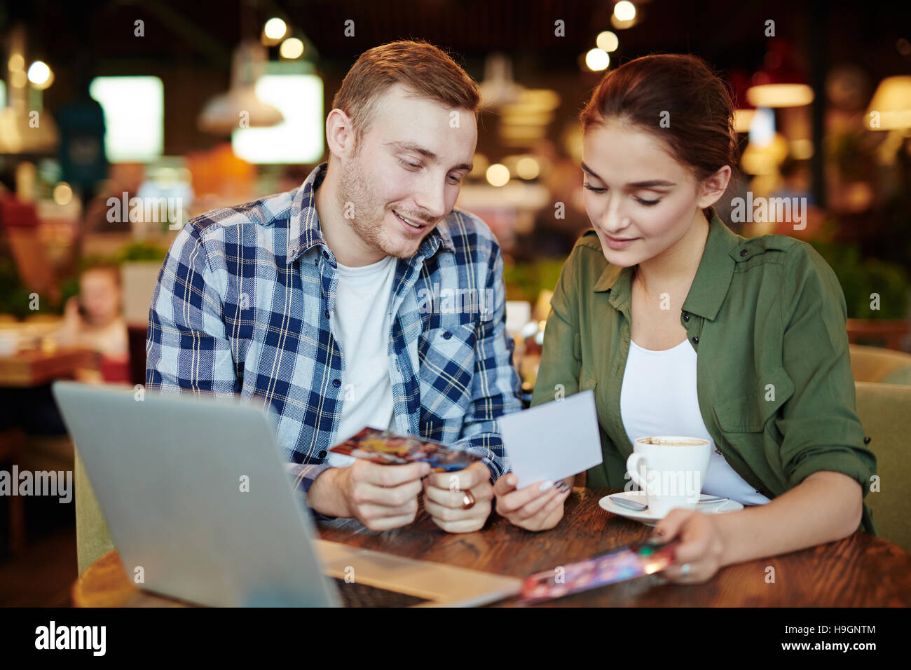 Guy and girl looking photographs in cafe Stock Photo - Alamy