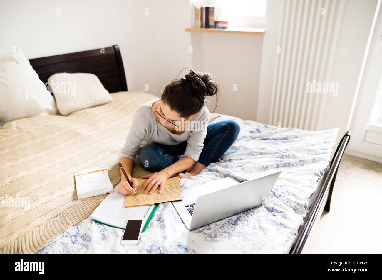 Beautiful young woman sitting on bed, working. Home office Stock Photo ...