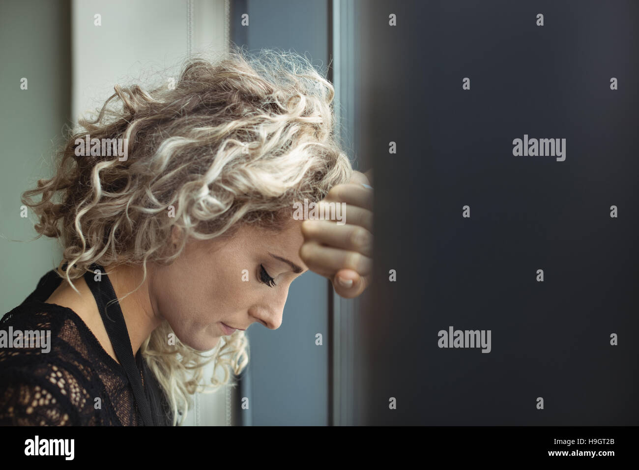 Upset businesswoman leaning on window Stock Photo - Alamy