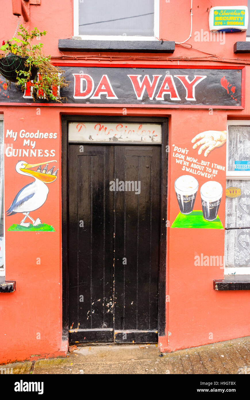 Guinness advertising painted on the orange wall outside an Irish pub ...