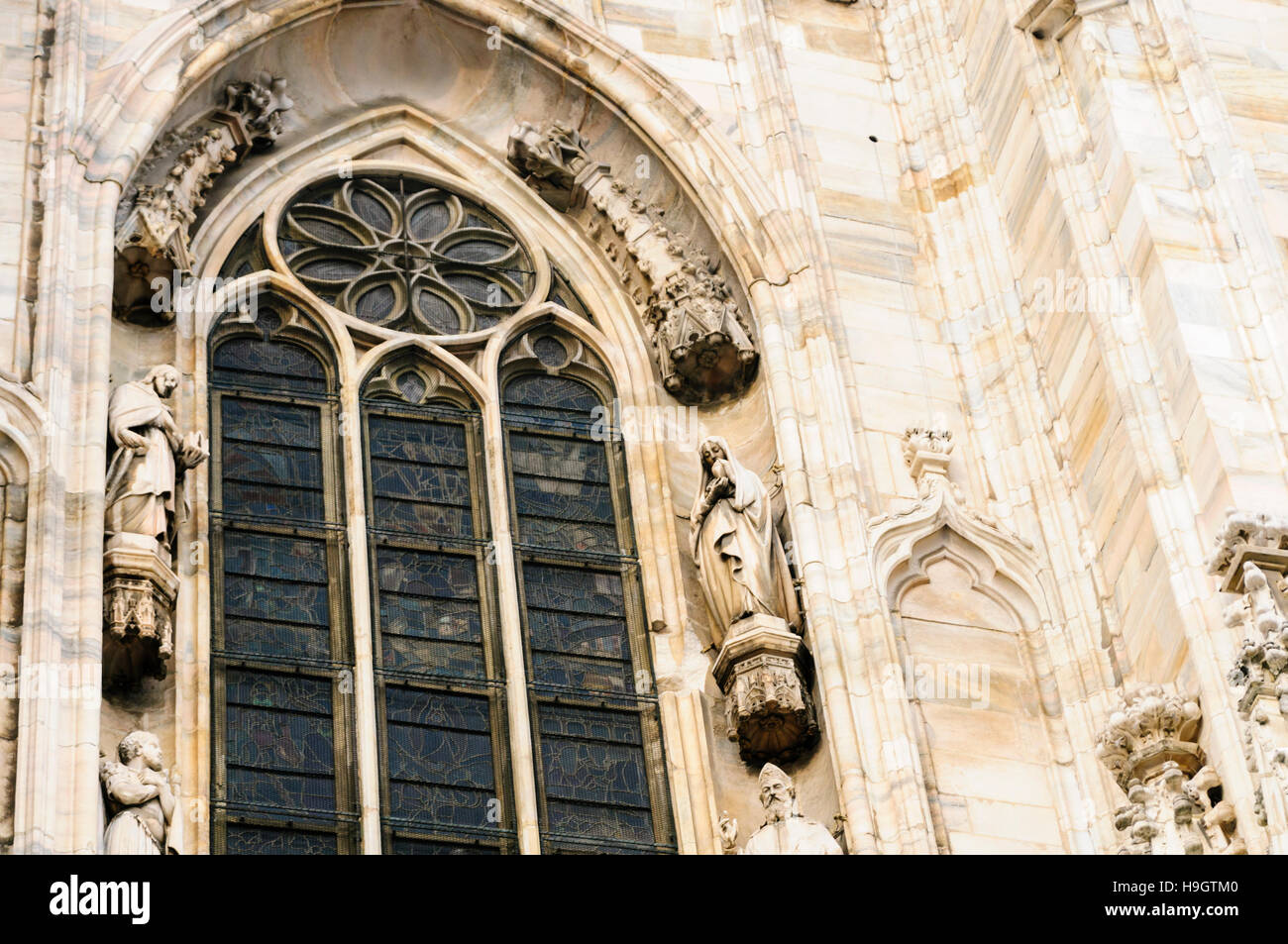 Ornate carvings around a stained glass window at the Duomo Milano ...