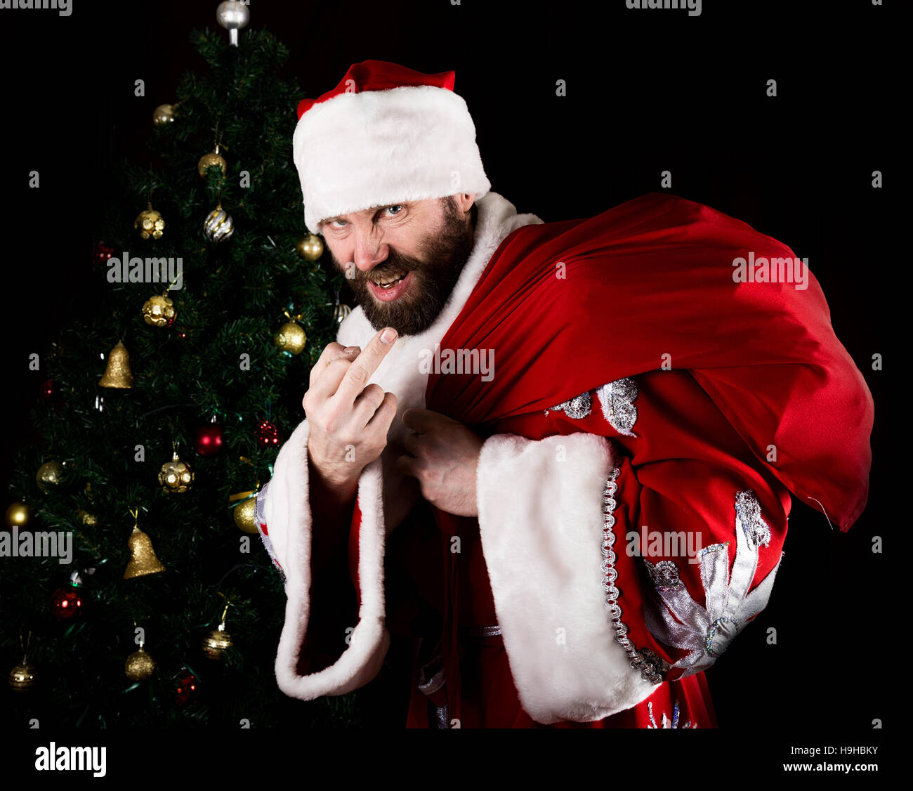 bad brutal Santa Claus carries a bag, showing middle finger and smiling ...