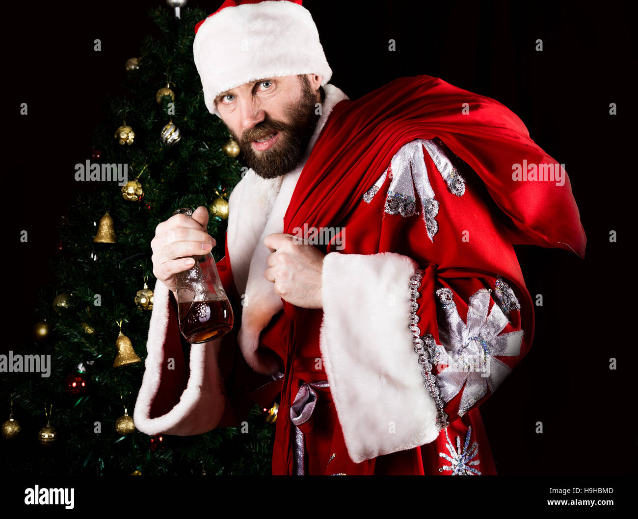 bad brutal Santa Claus carries a bag, smiling spitefully and drinking ...