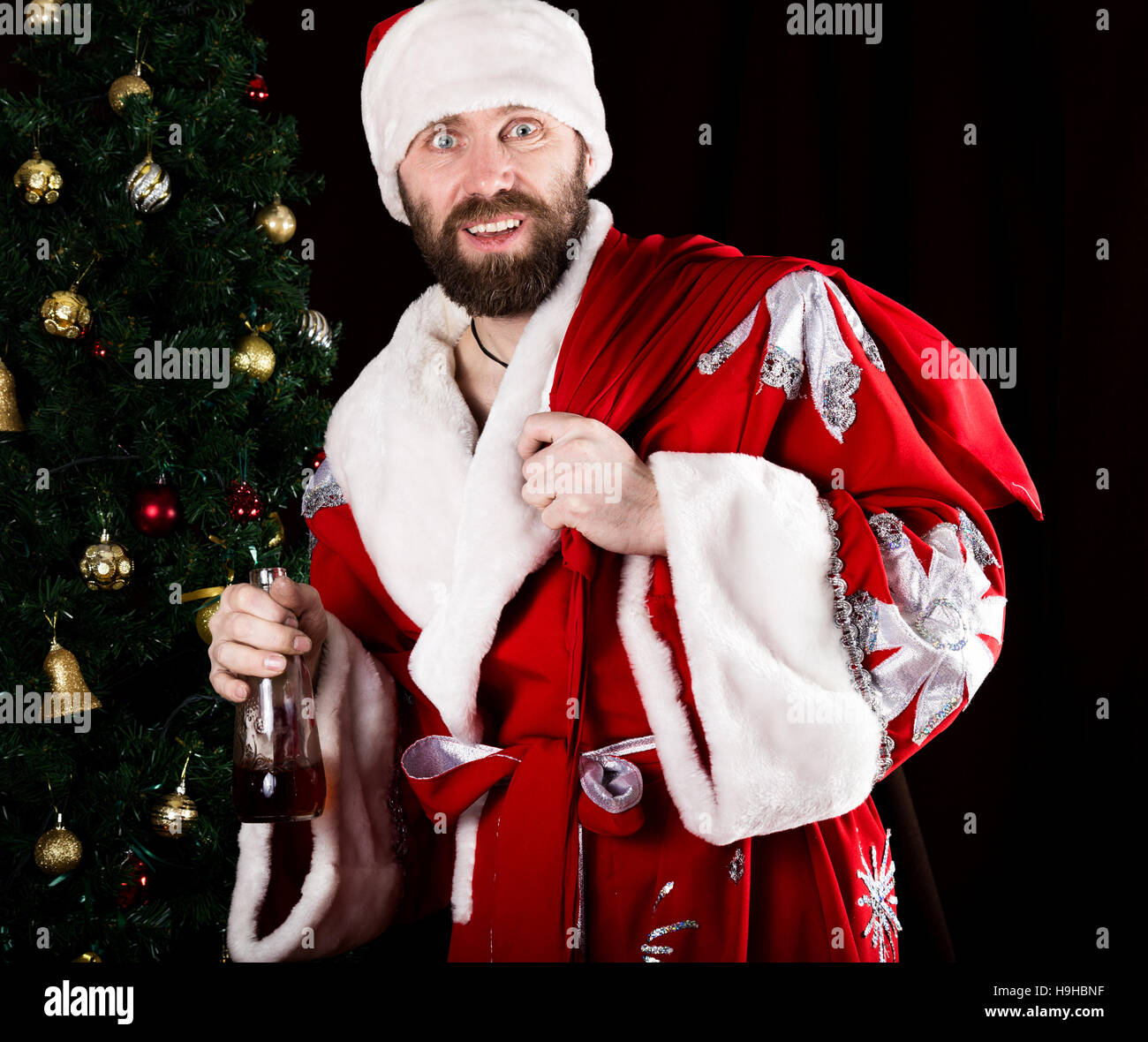 bad brutal Santa Claus carries a bag, smiling spitefully and drinking ...