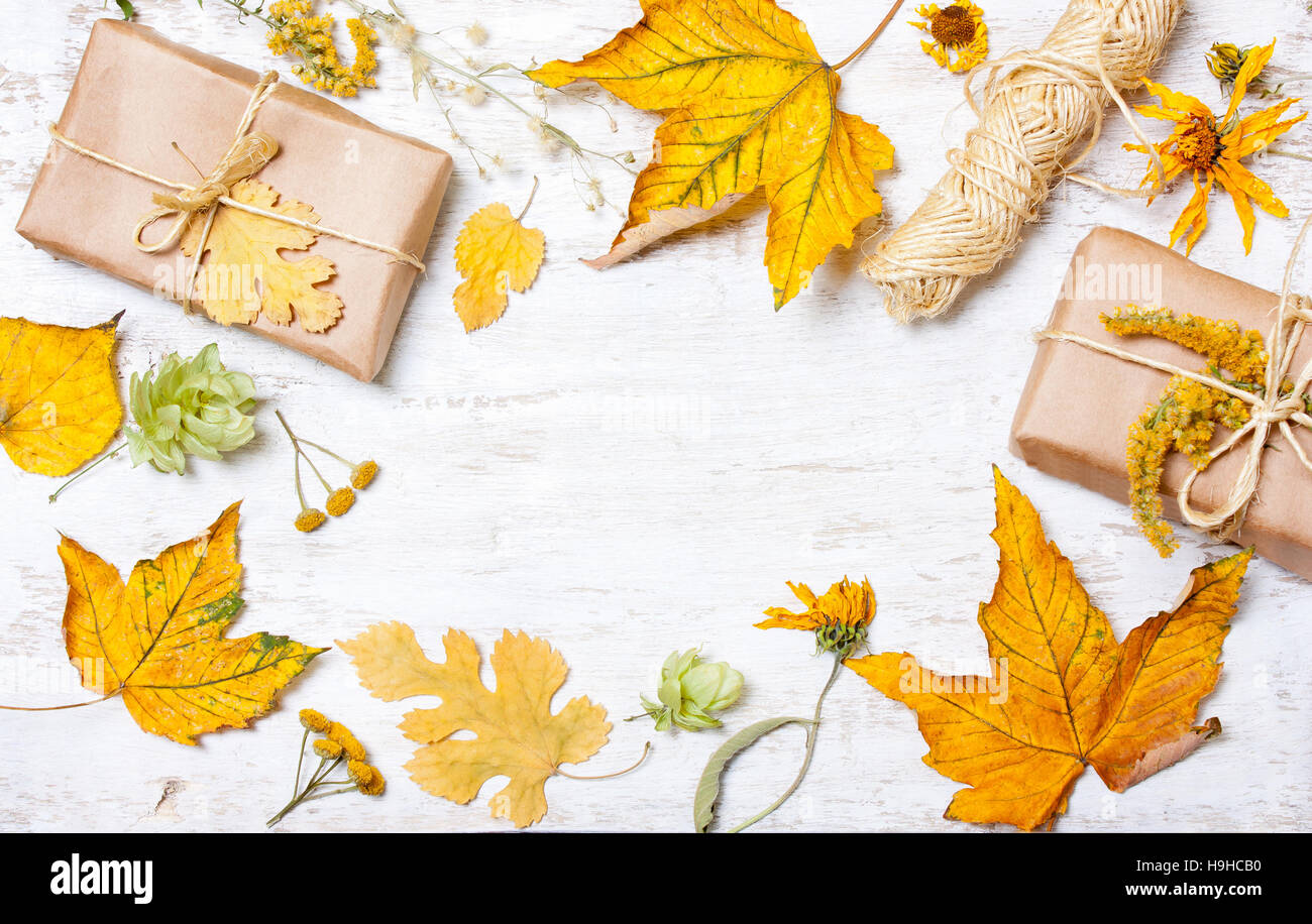 Composition of gifts and yellow leaves on a white wooden background ...