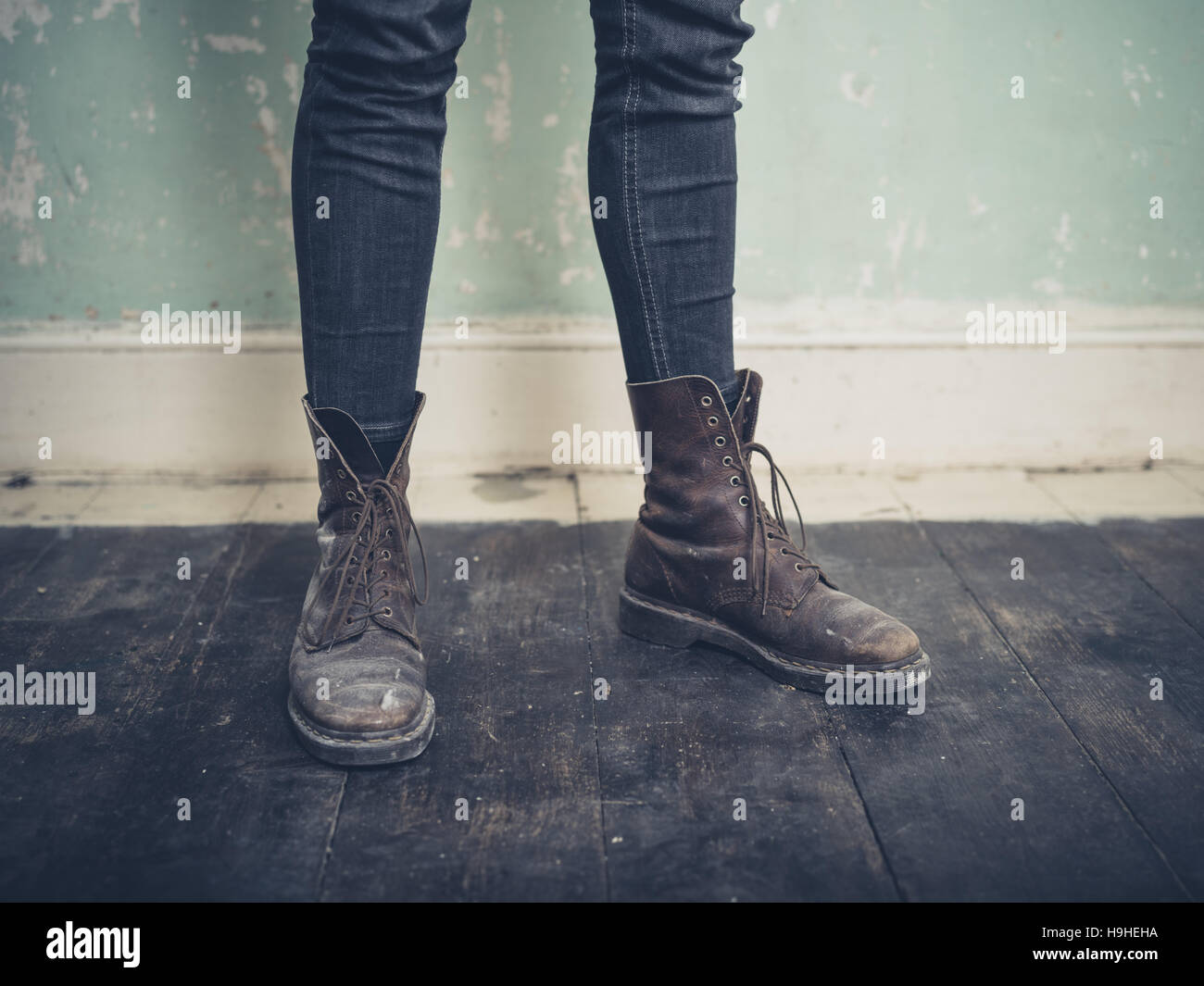 A young person wearing leather boots is standing in an empty room Stock ...