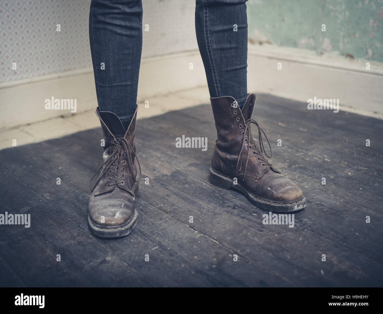 A young person wearing leather boots is standing in an empty room Stock ...