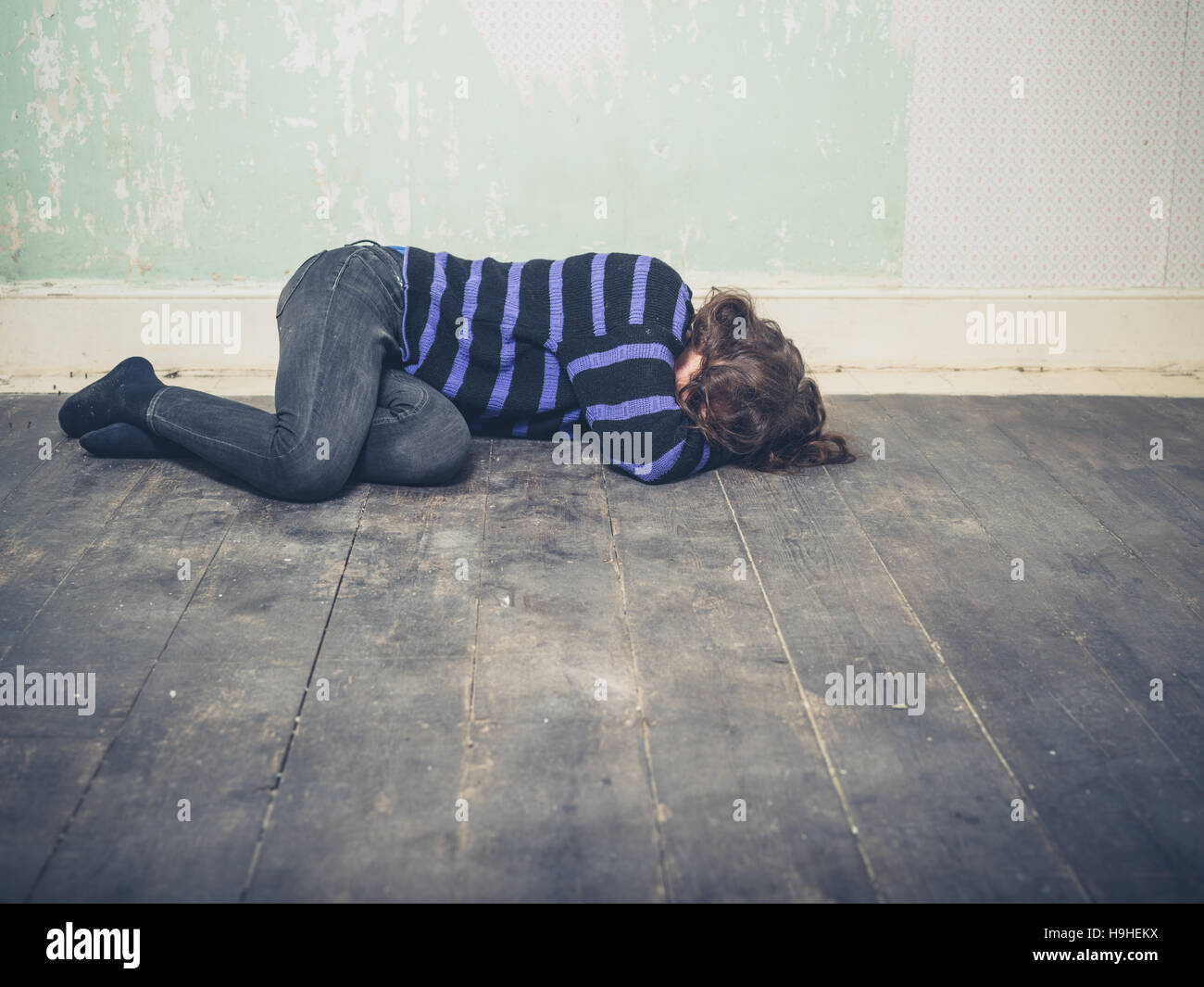 A sad young woman is lying on the floor in an empty room Stock Photo ...