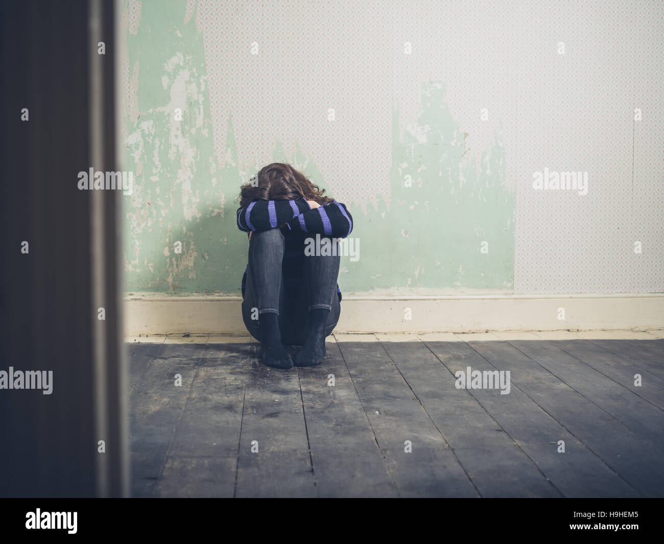 A sad young woman is sitting on the floor in an empty room Stock Photo ...
