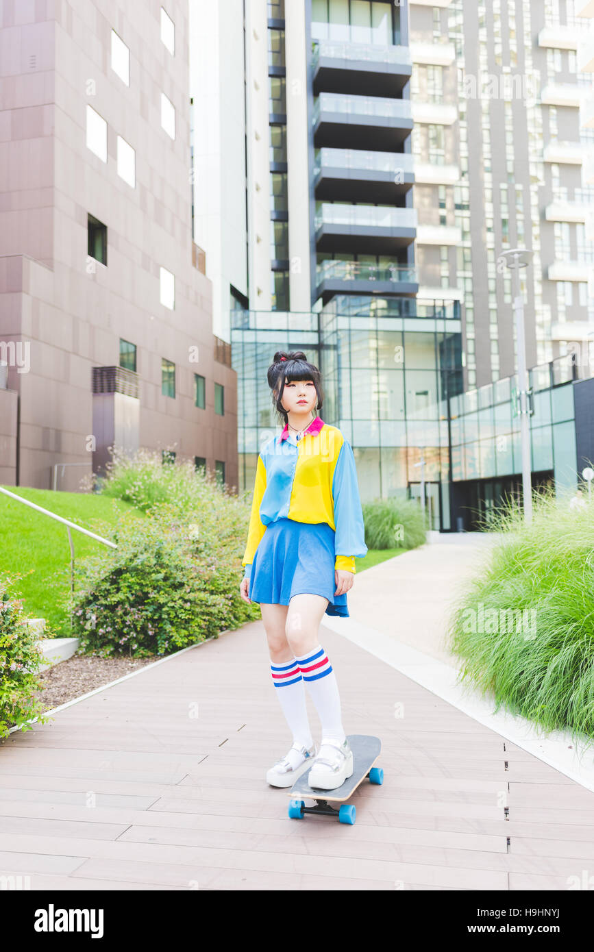 young beautiful asian millennial woman nonconformist skating outdoor in the city - skater ...