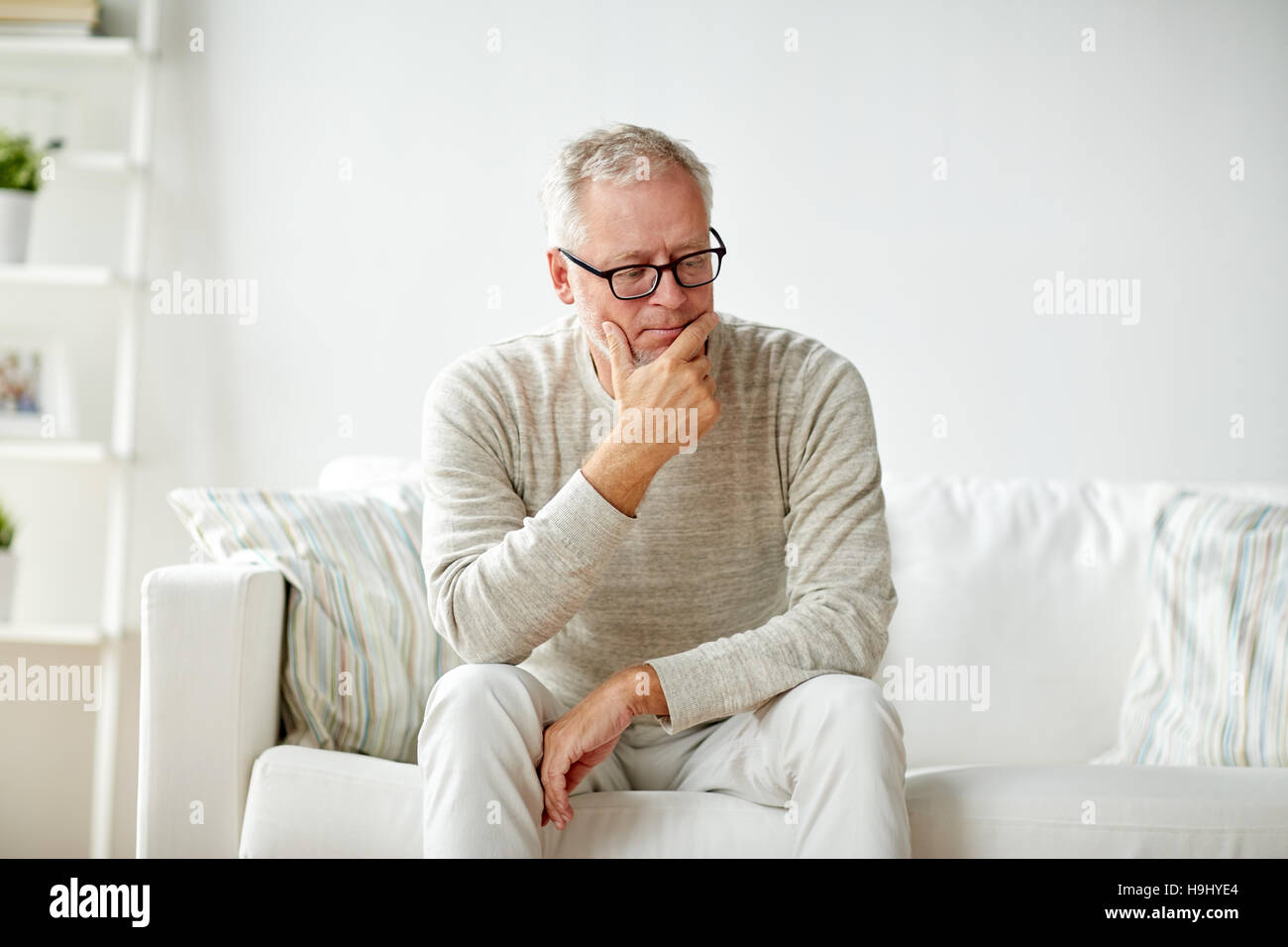 senior man sitting on sofa at home and thinking Stock Photo - Alamy