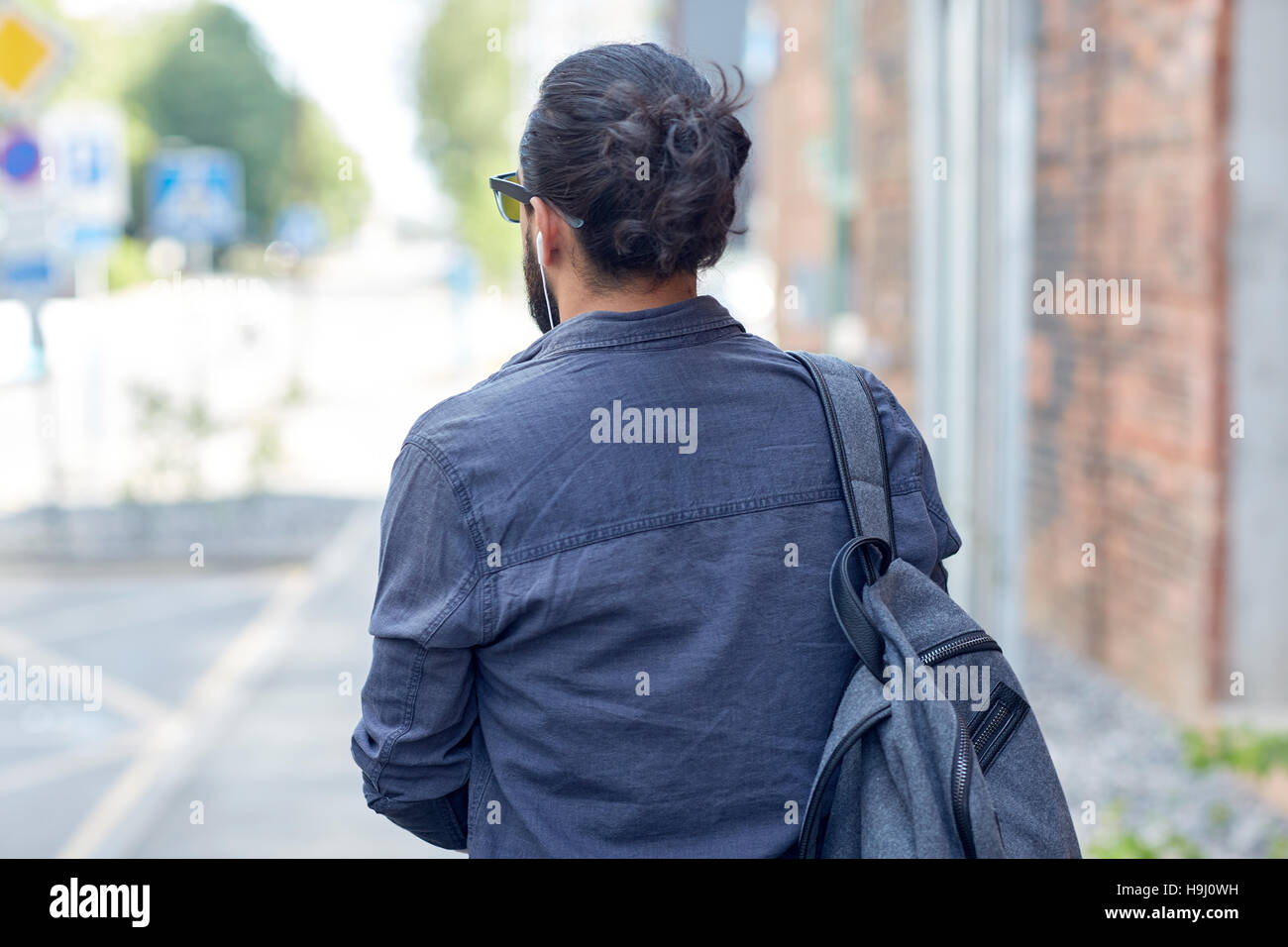 man with backpack walking along city street Stock Photo - Alamy