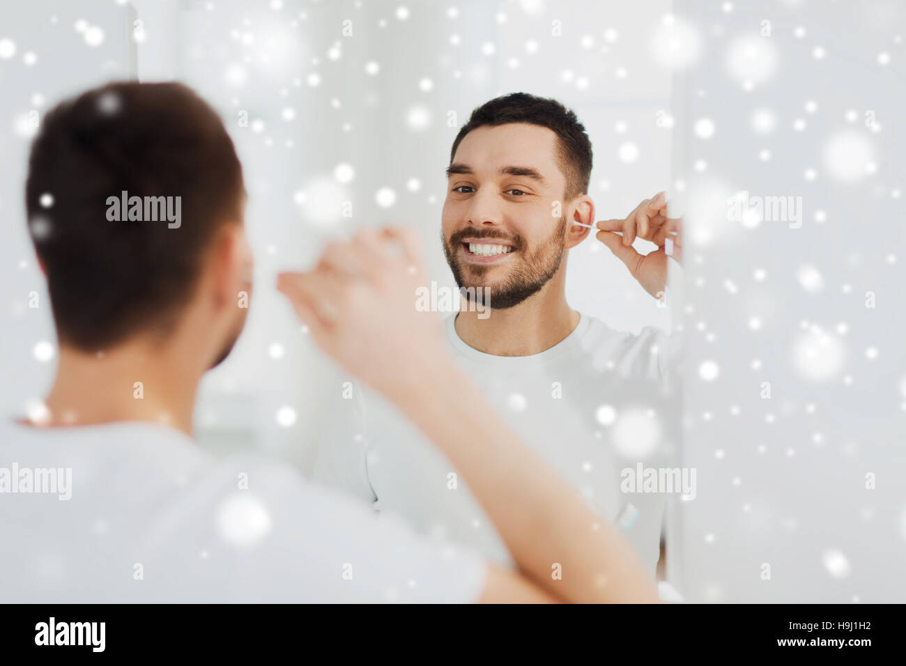 man cleaning ear with cotton swab at bathroom Stock Photo - Alamy