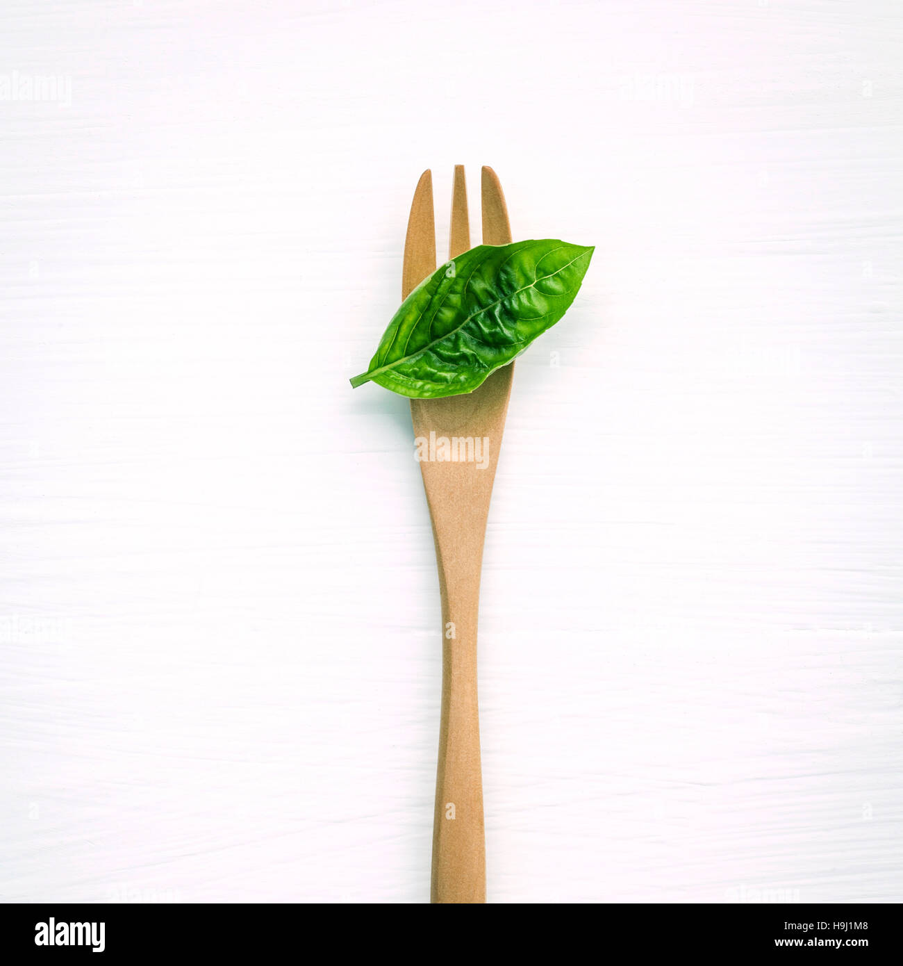 Closeup fresh sweet basil leaves with fork on white wooden bac Stock ...