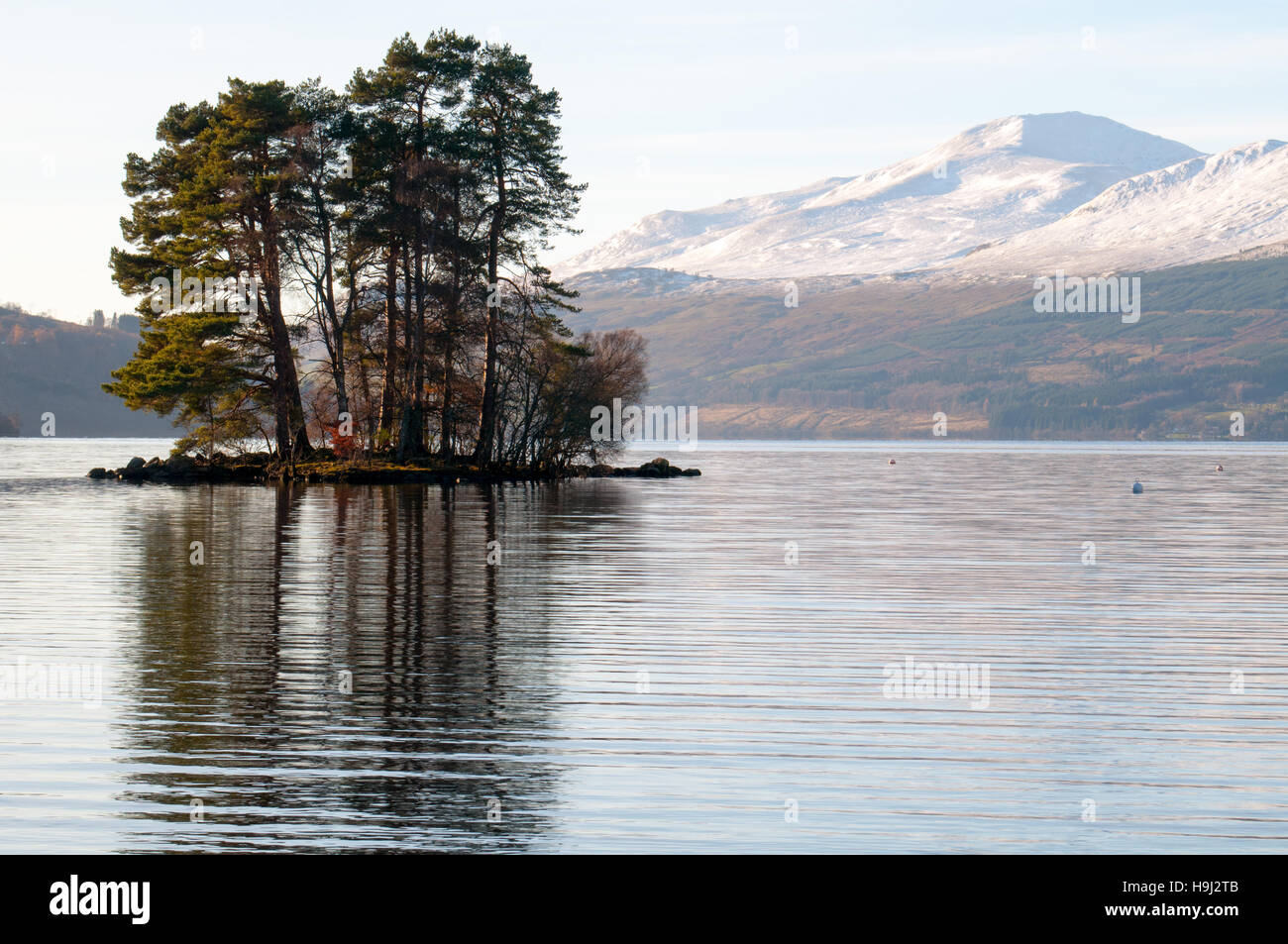 Small island on loch Tay, Perthshire with snow coveed mountains in the ...