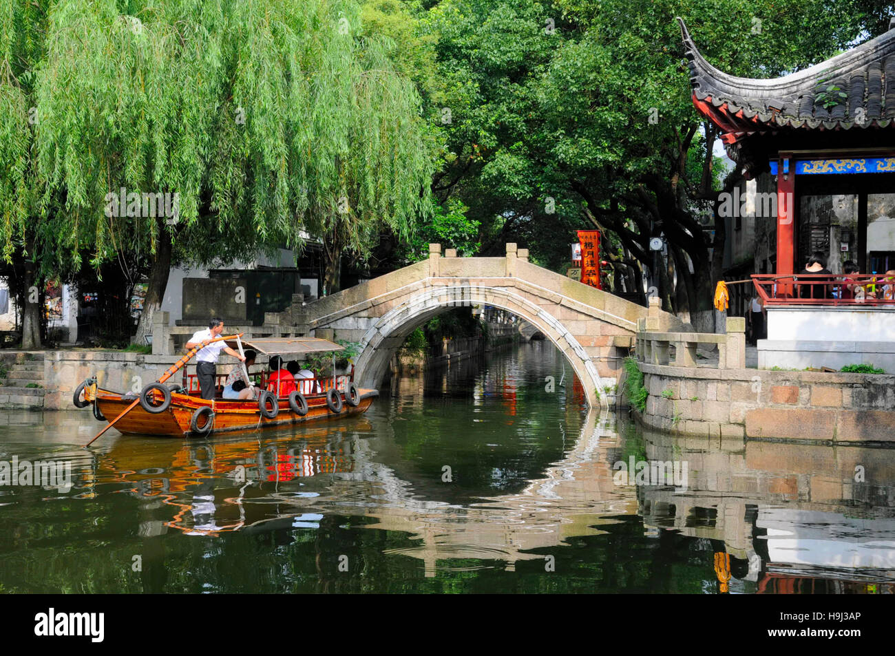 July 25, 2015. Tongli Town, China. A tourist boat moving by Chinese architecture towards an ...