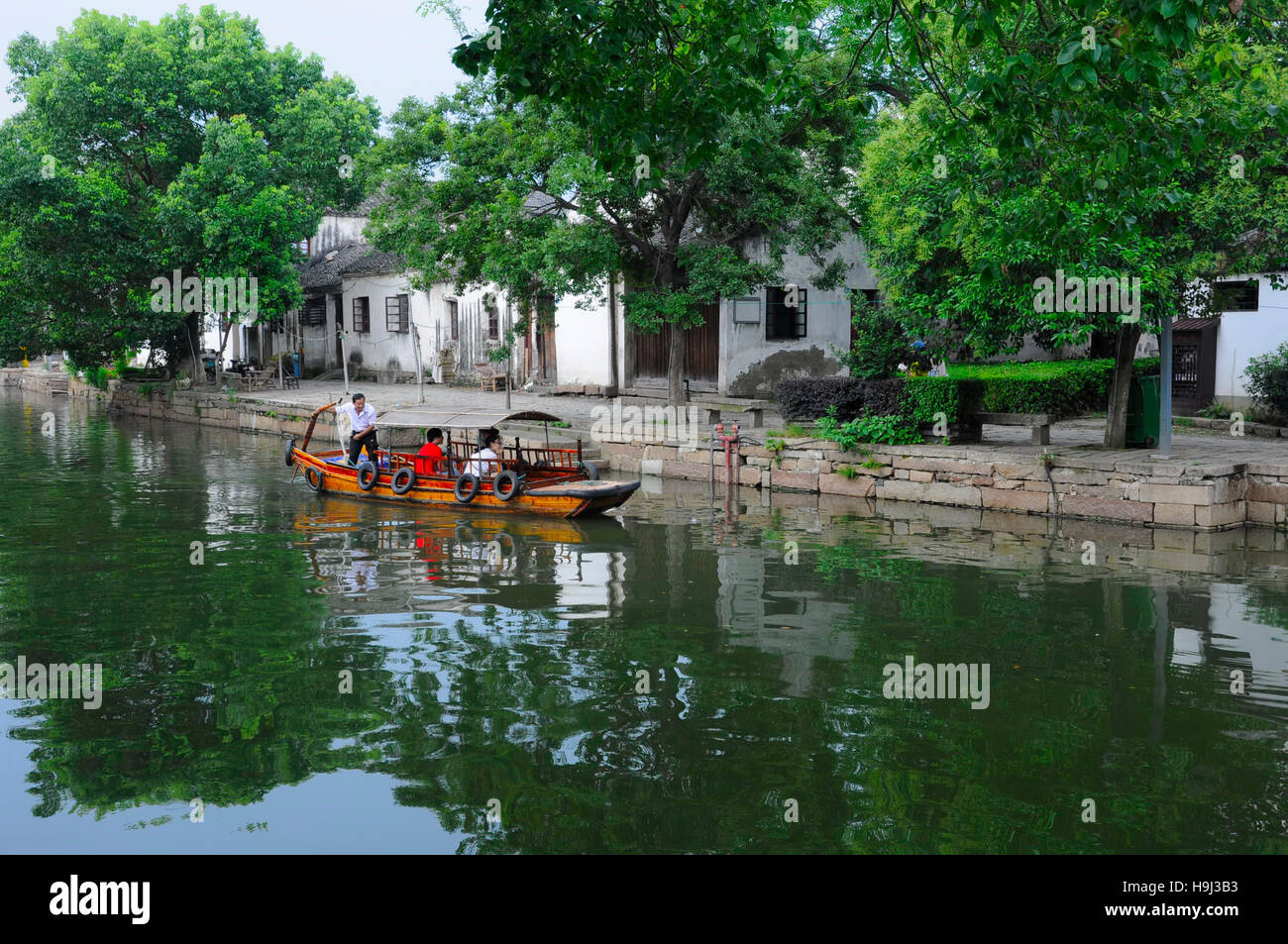 July 25, 2015. Tongli Town, China. A wooden tourist boat moving by Chinese architecture on the ...