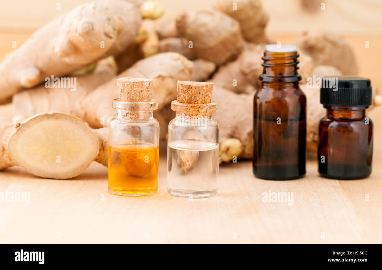 Bottles of ginger oil and ginger on wooden background with selec Stock ...