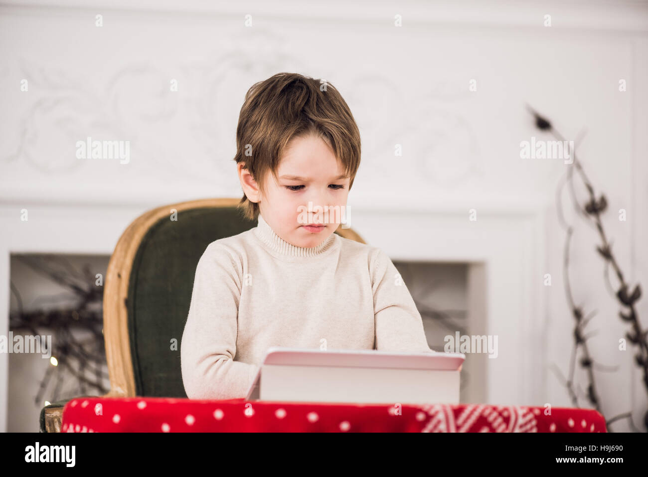 Portrait of cute kid boy sitting on green chair and playing with ...