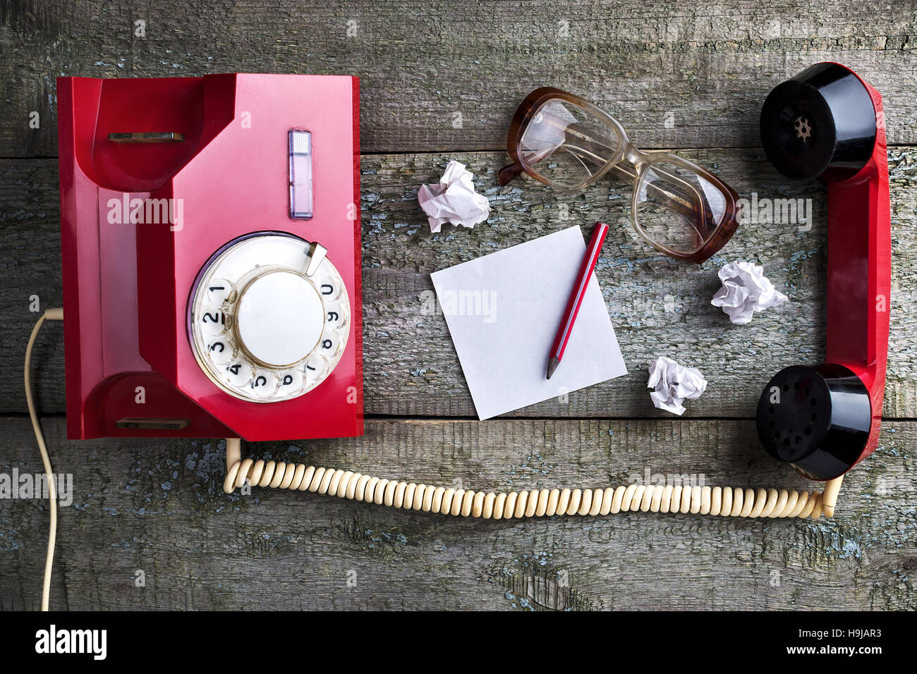Old glasses with sheet for notes, pencil and red vintage phone on ...