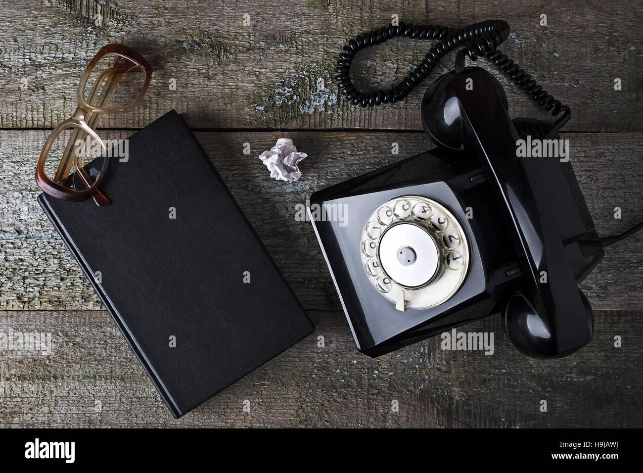 Black vintage phone, old glasses and notebook on wooden background ...