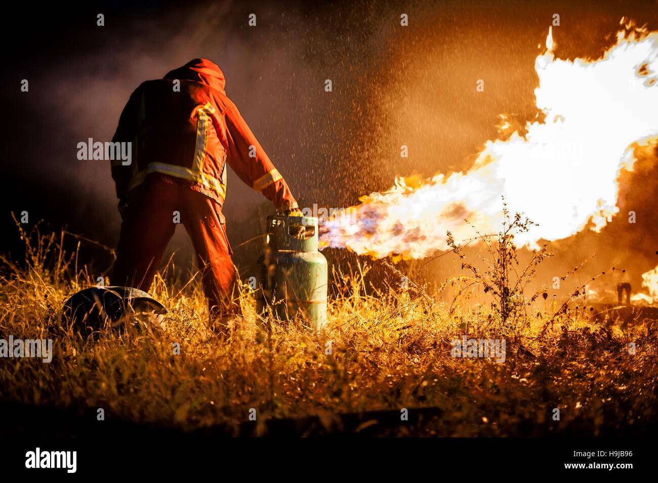 Silhouette of Firemen fighting a raging fire with huge flames of ...