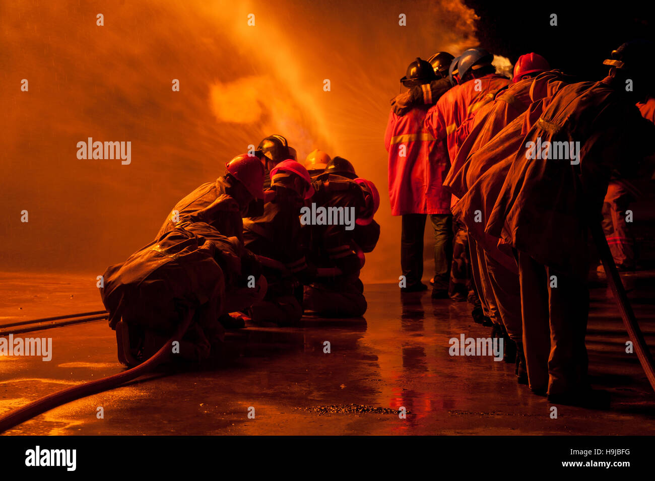 Silhouette of Firemen fighting a raging fire with huge flames of ...
