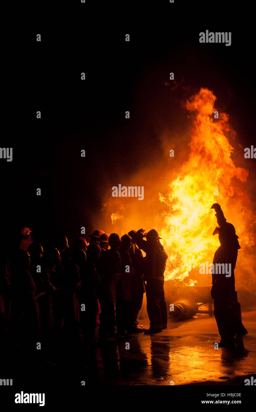 Silhouette of Firemen fighting a raging fire with huge flames of ...