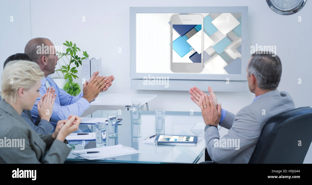 Composite image of business team applauding and looking at white screen ...