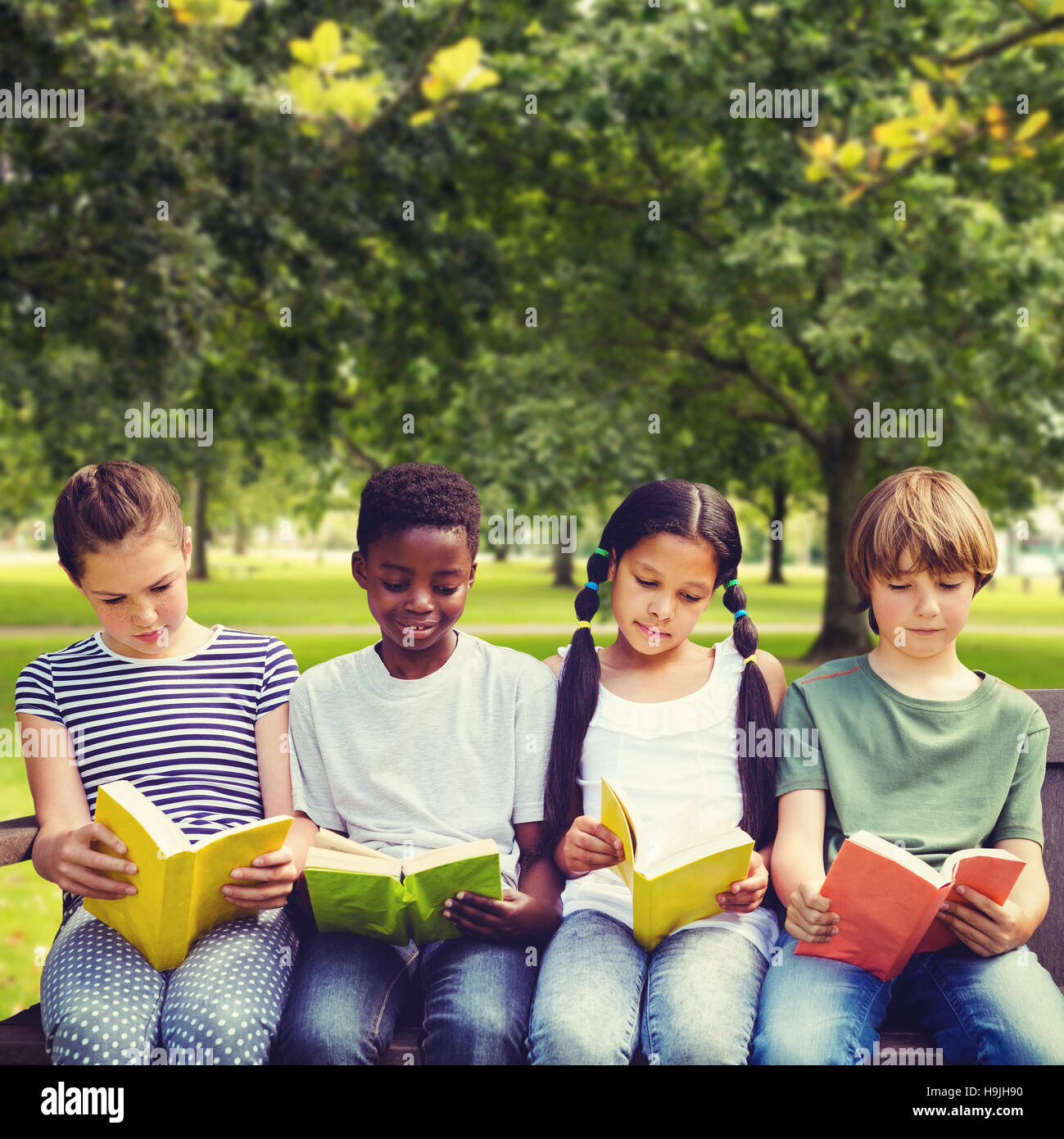 Composite image of children reading books at park Stock Photo - Alamy