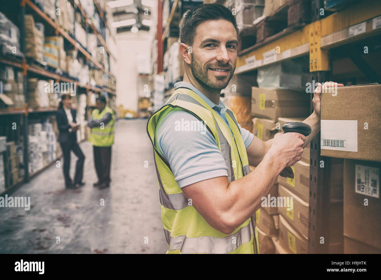 Warehouse worker scanning box while smiling at camera Stock Photo - Alamy