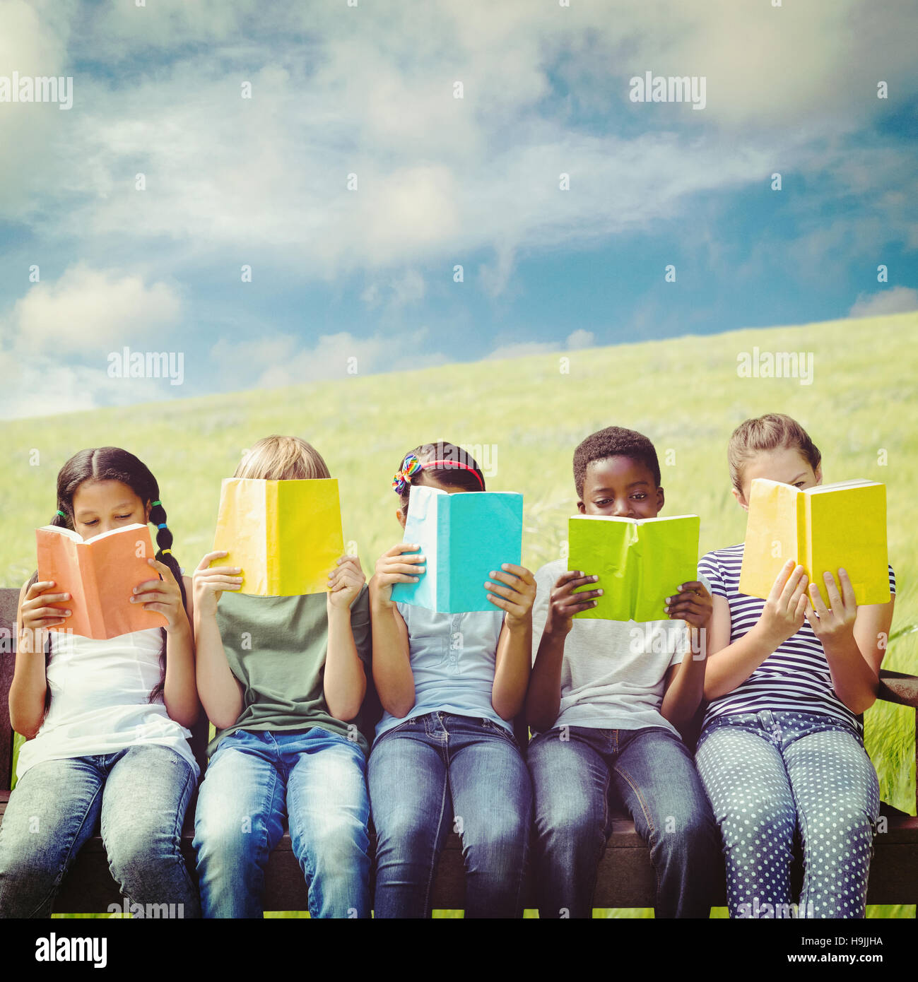 Composite image of children reading books at park Stock Photo - Alamy