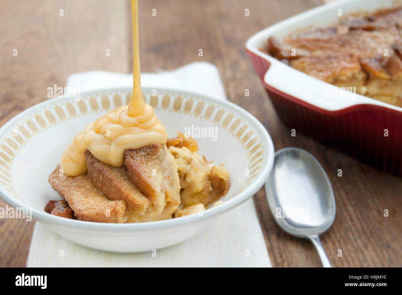 Pouring Custard on a serving of Bread and Butter Pudding, served in a ...