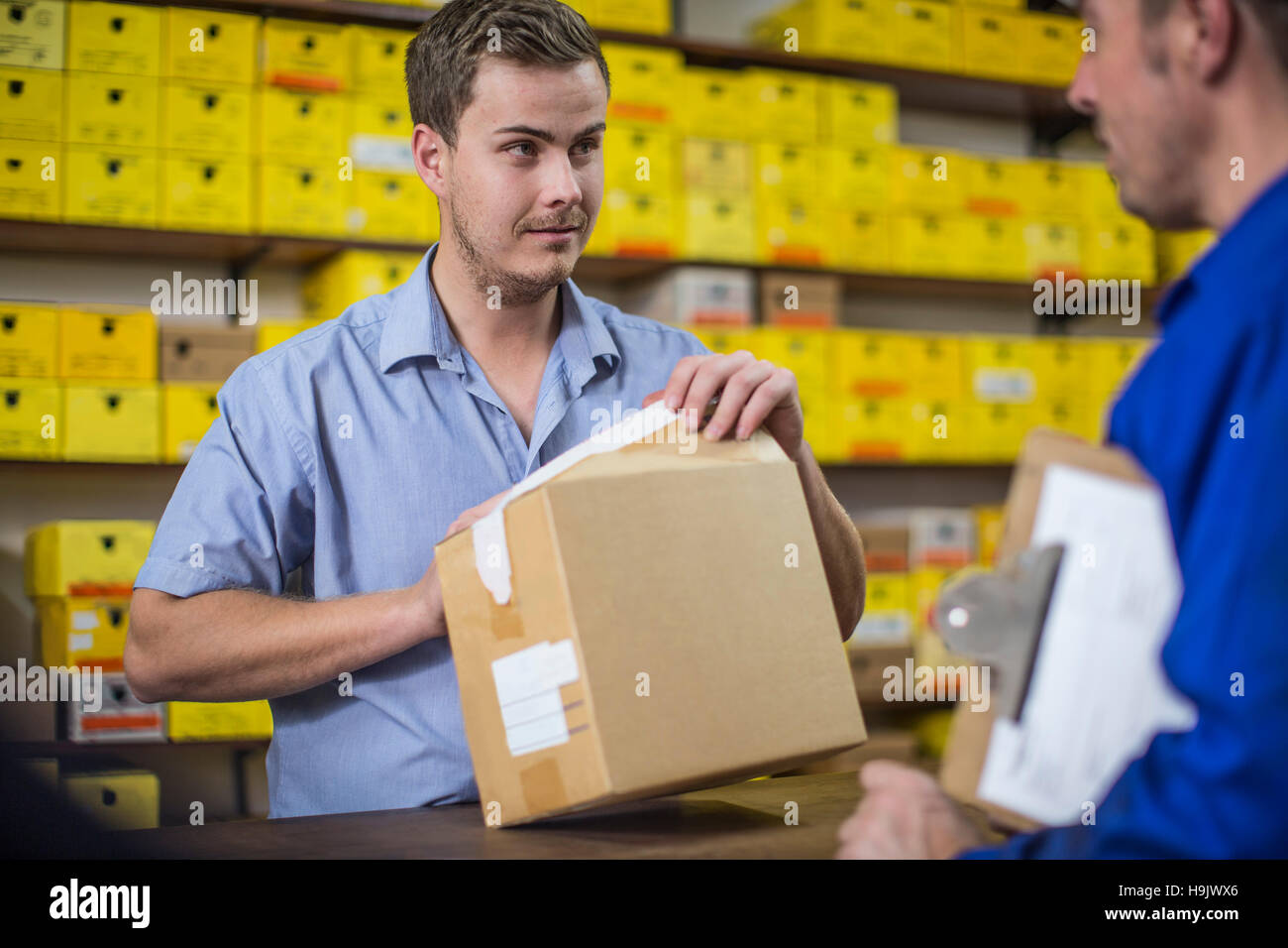 Man in warehouse checking delivered cardboard box Stock Photo - Alamy