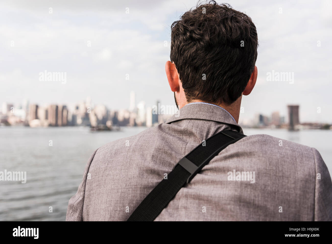 USA, New York City, back view of man at East River looking on Manhattan ...