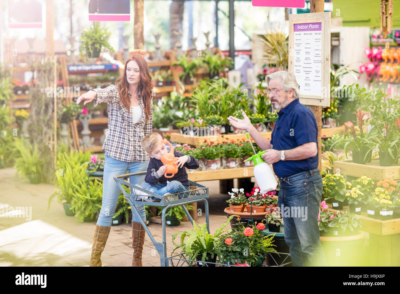 Gardener helping clients at garden centre Stock Photo - Alamy