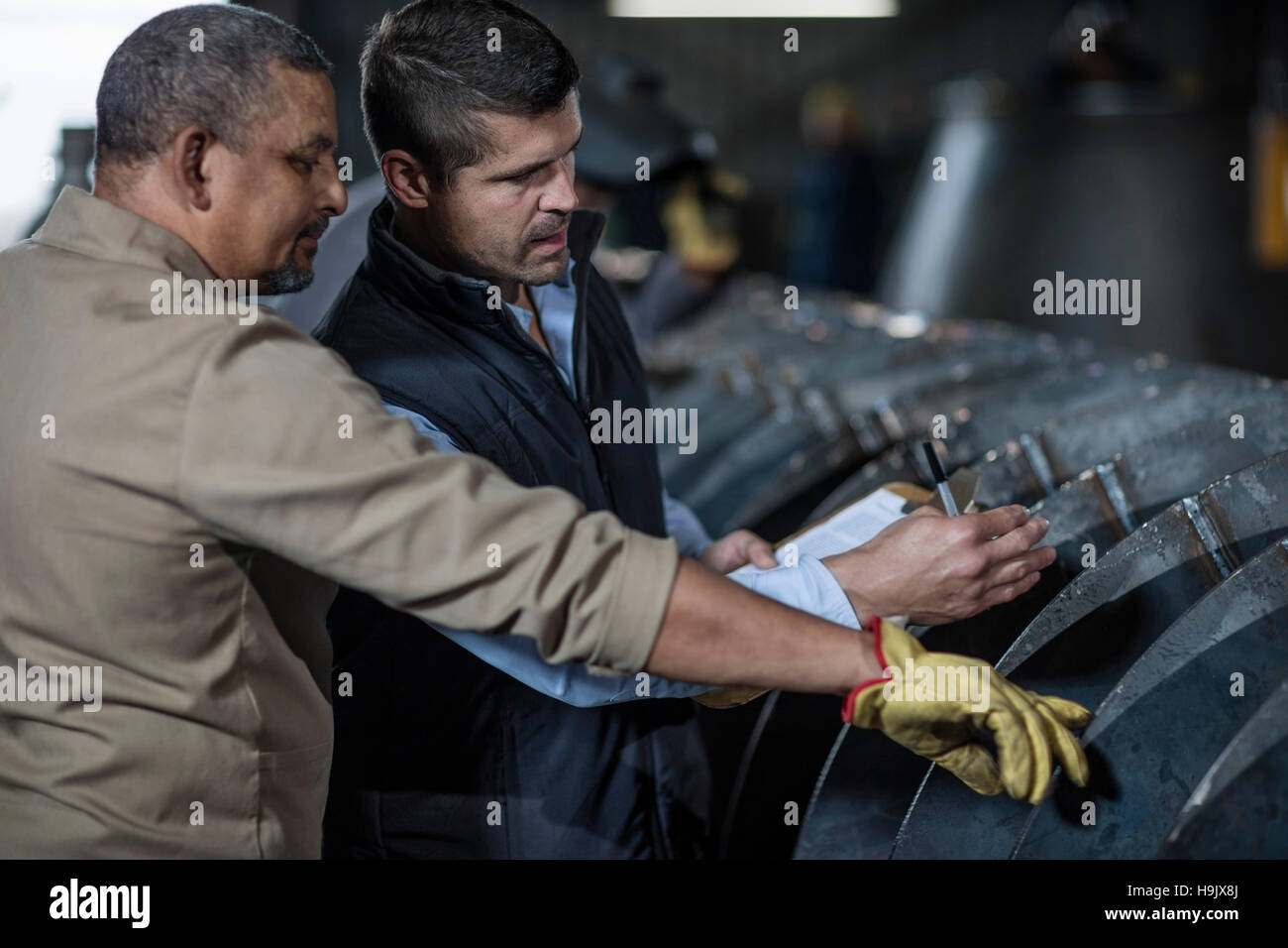 Metal workers examining components Stock Photo - Alamy