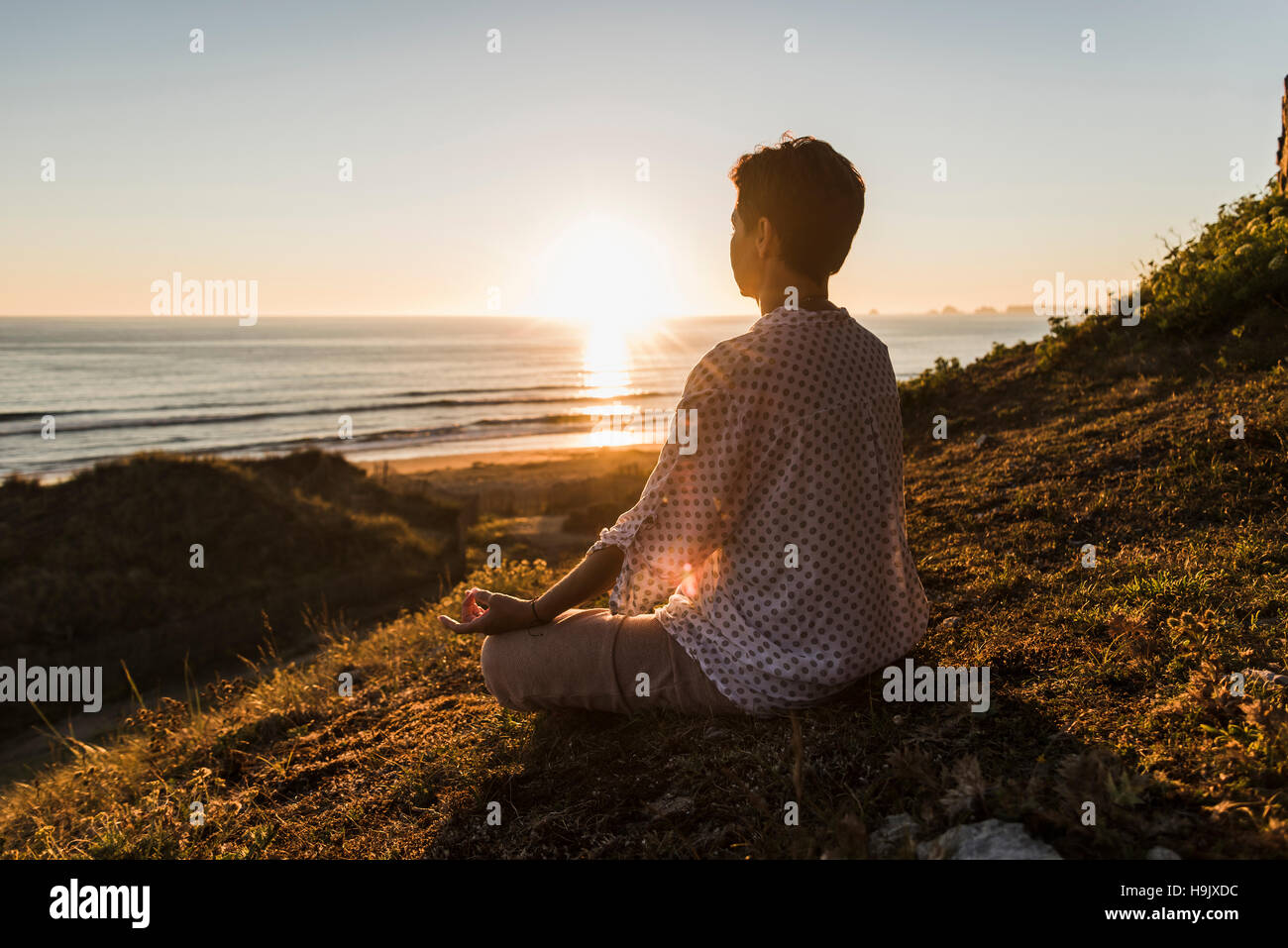 Back view of woman meditating at sunset Stock Photo - Alamy