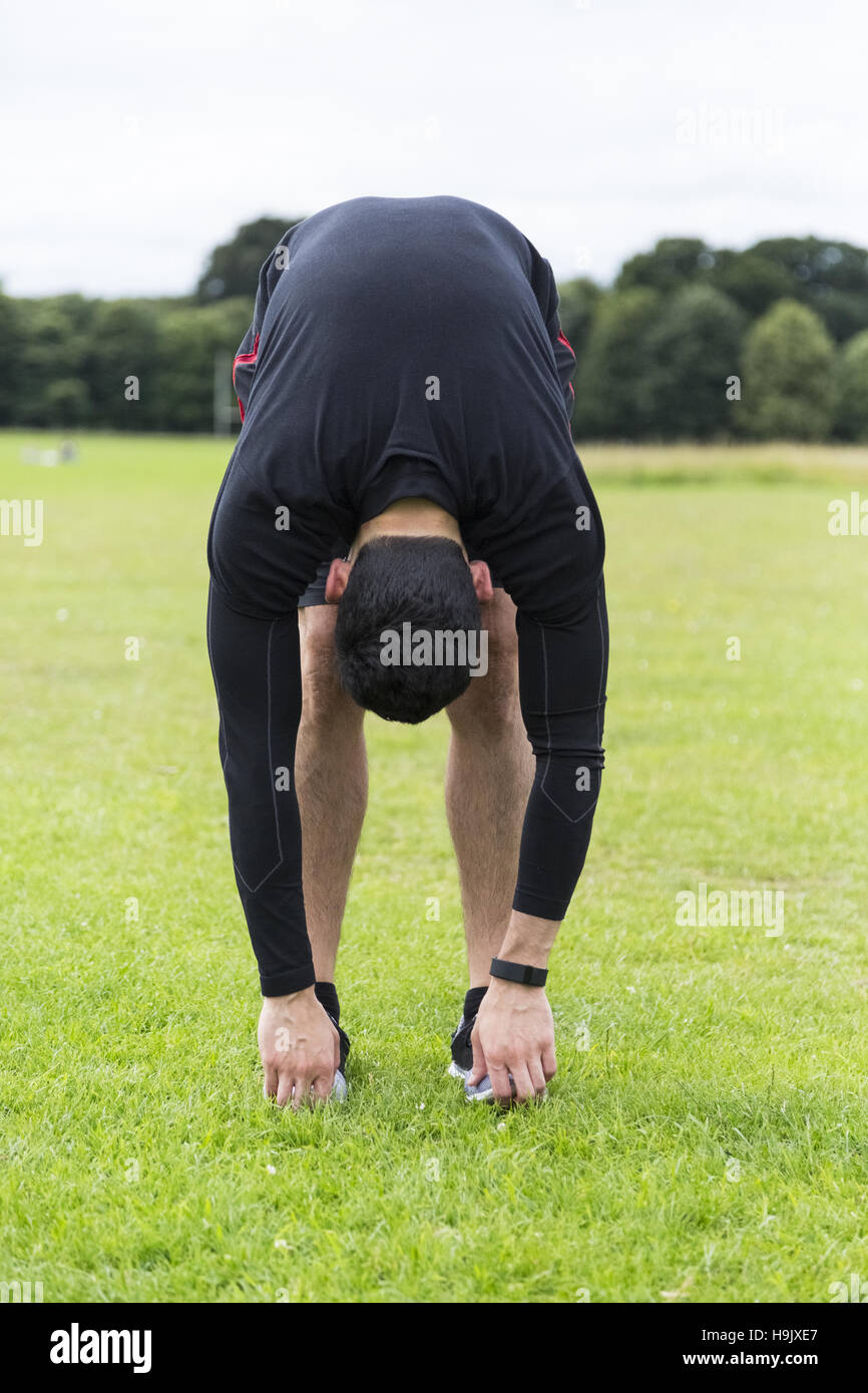 Athlete stretching in grass Stock Photo - Alamy