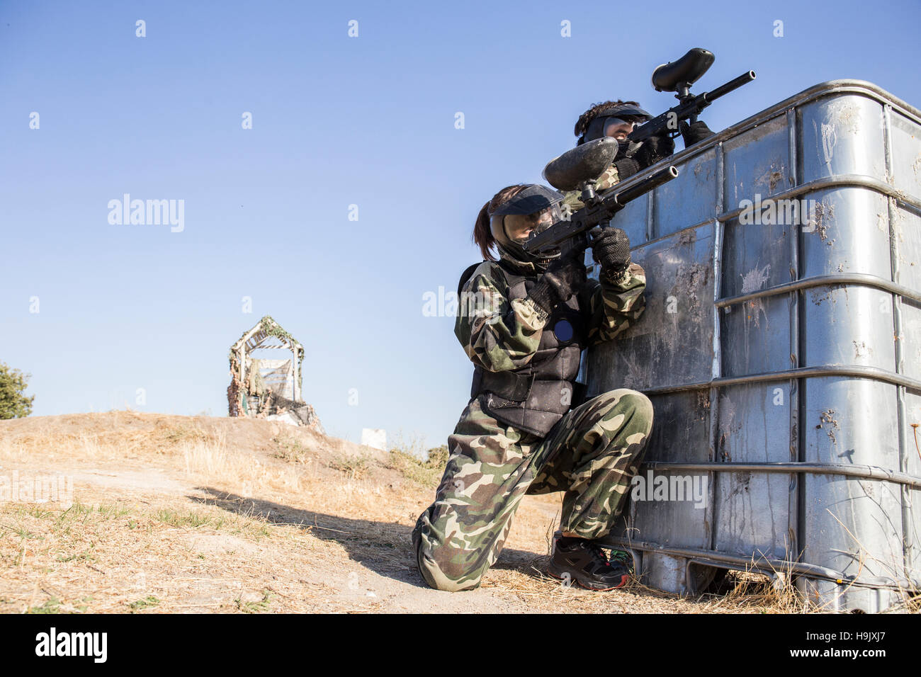 Paintball players aiming with paintball guns during a paintball game ...