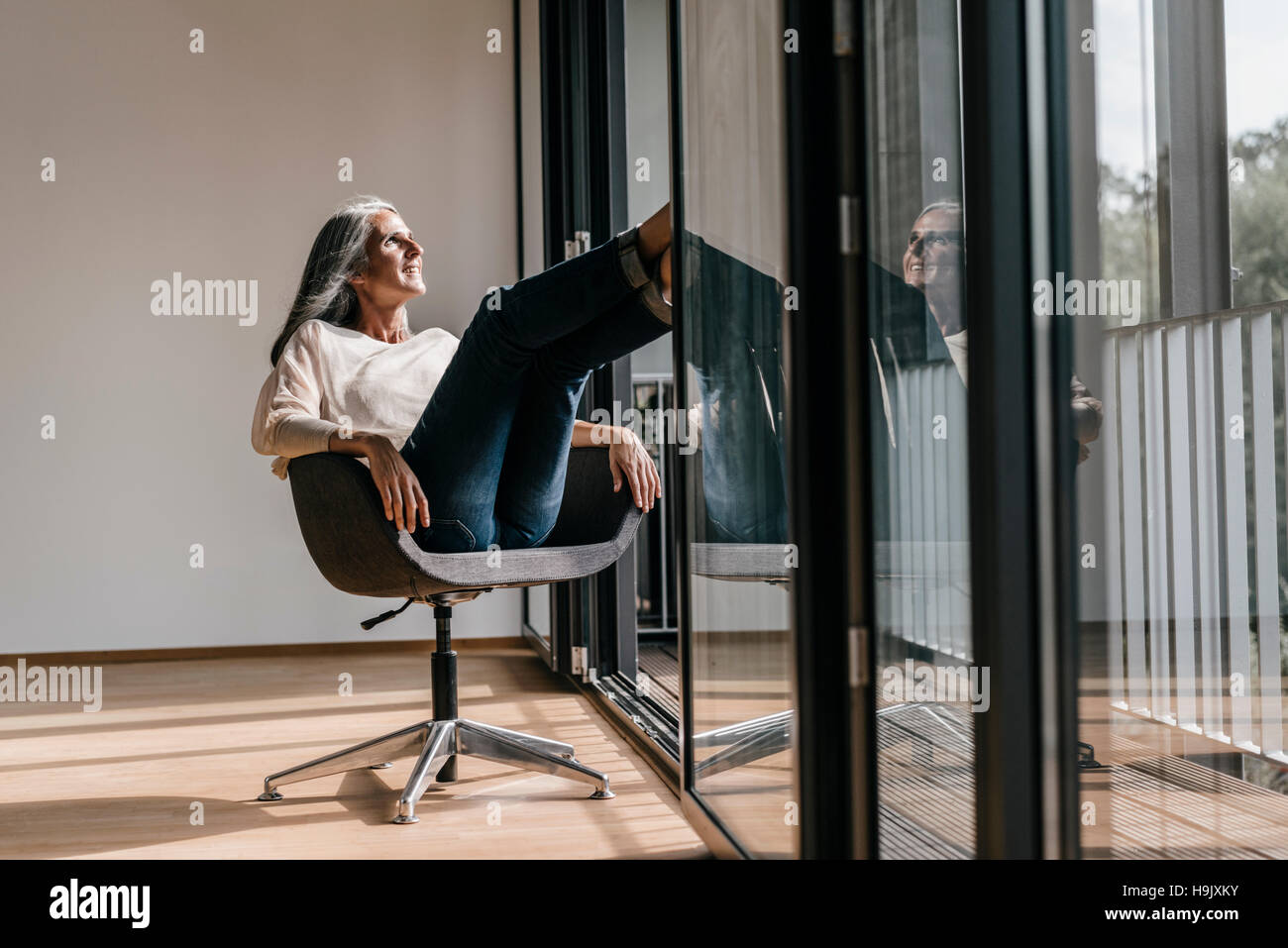 Woman with long grey hair sitting on chair at the window Stock Photo - Alamy