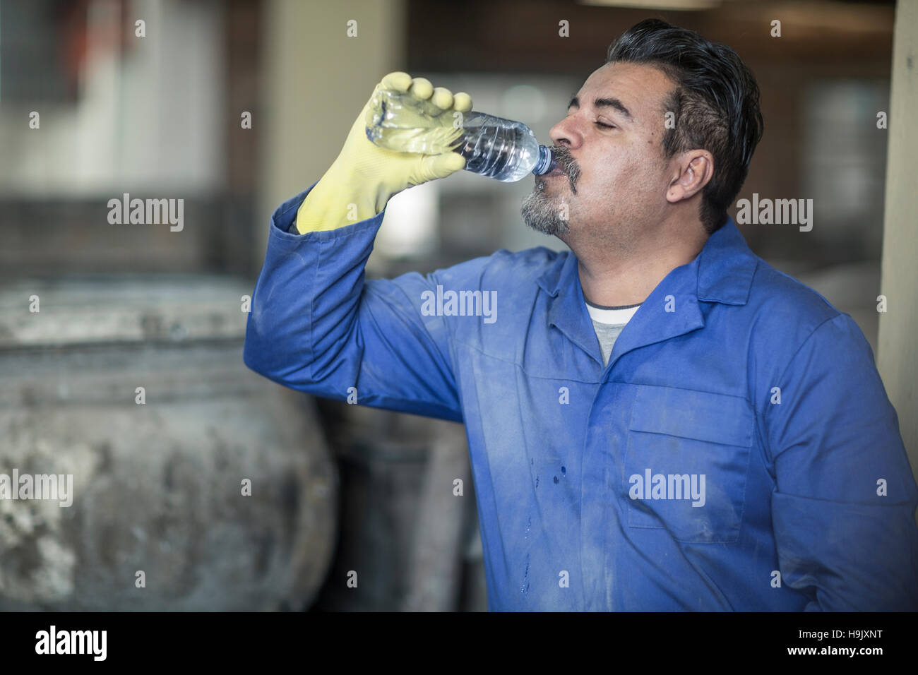 Worker drinking water from bottle in industrial factory Stock Photo - Alamy