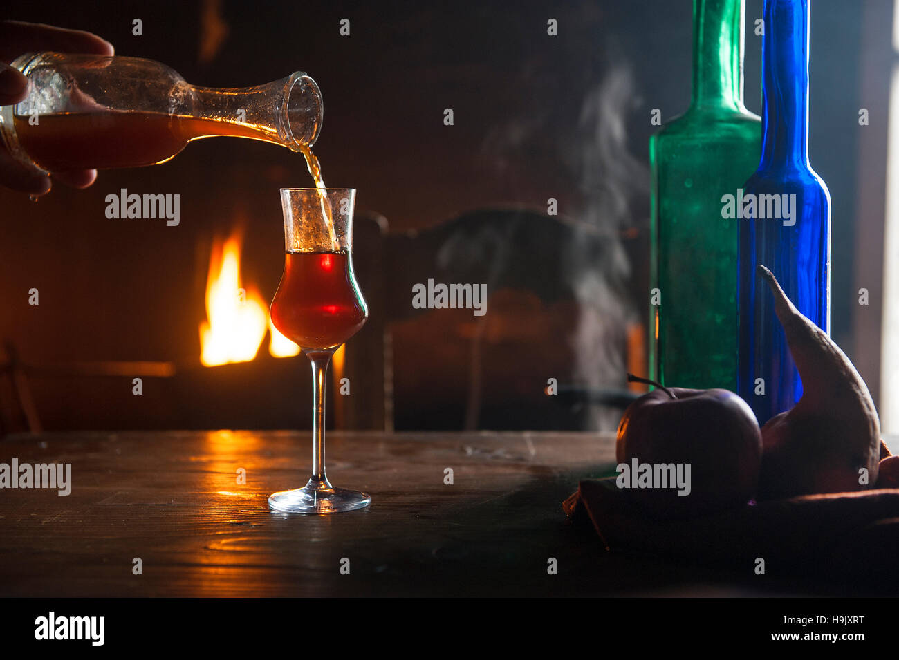 Hand pouring liqueur into shot glass in front of open fire Stock Photo ...